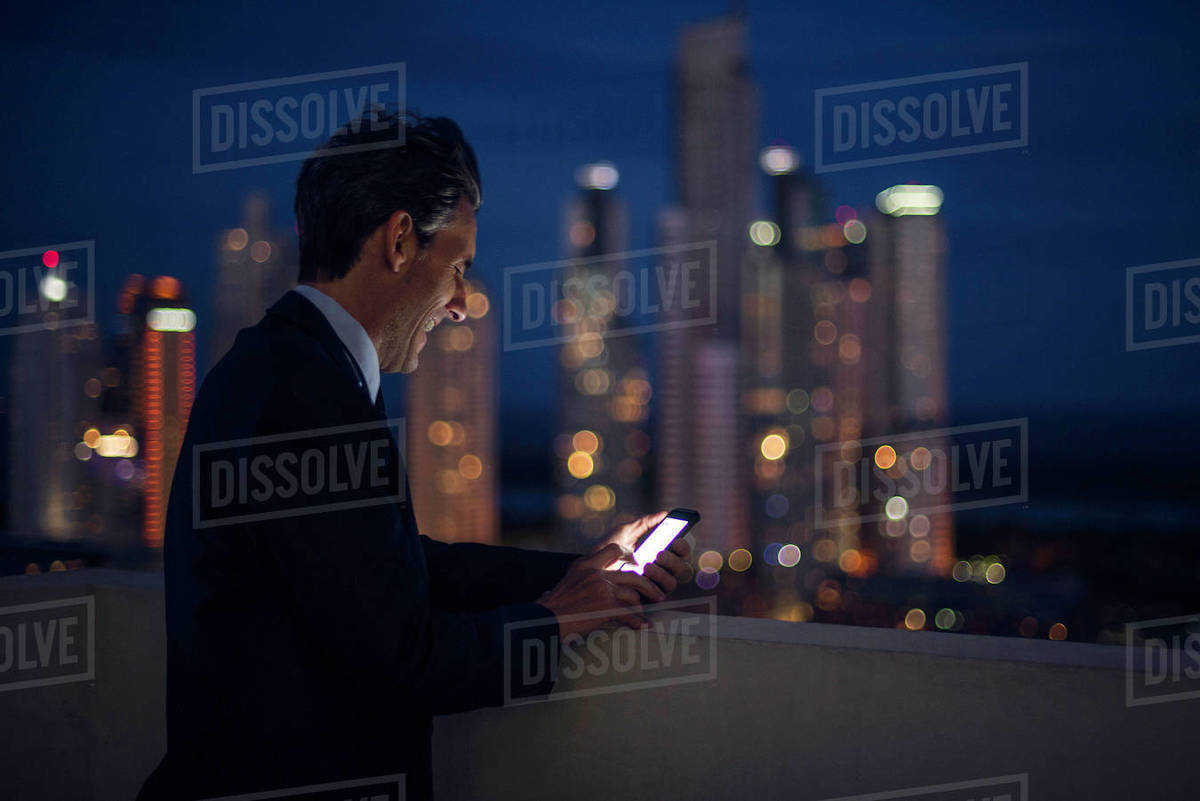 Businessman on high rise rooftop using mobile phone - Royalty-free ...
