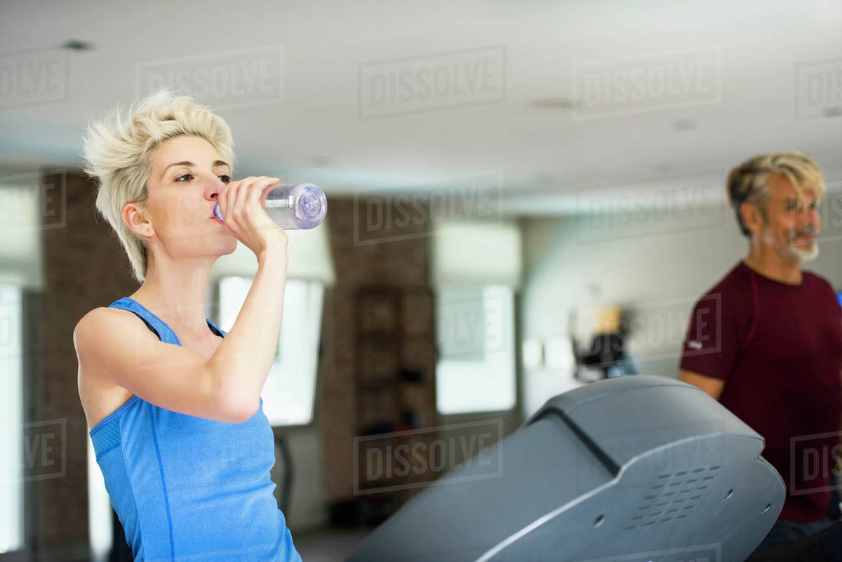 Woman drinking water while exercising on treadmill - Royalty-free Stock ...