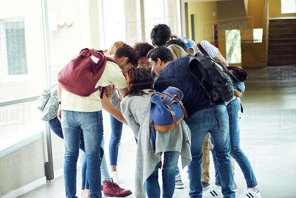 Group of students bending forward in a circle together in school ...