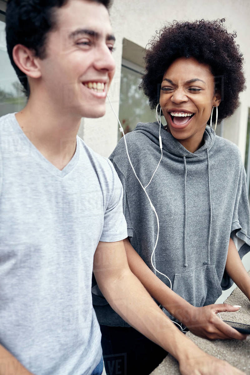 Friends listening to earphones and laughing together - Stock Photo ...
