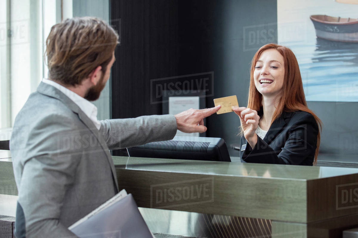Businessman giving credit card to female receptionist - Stock Photo ...