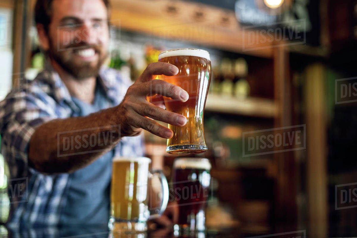 Smiling man serving beer - Royalty-free Stock Photo | Dissolve