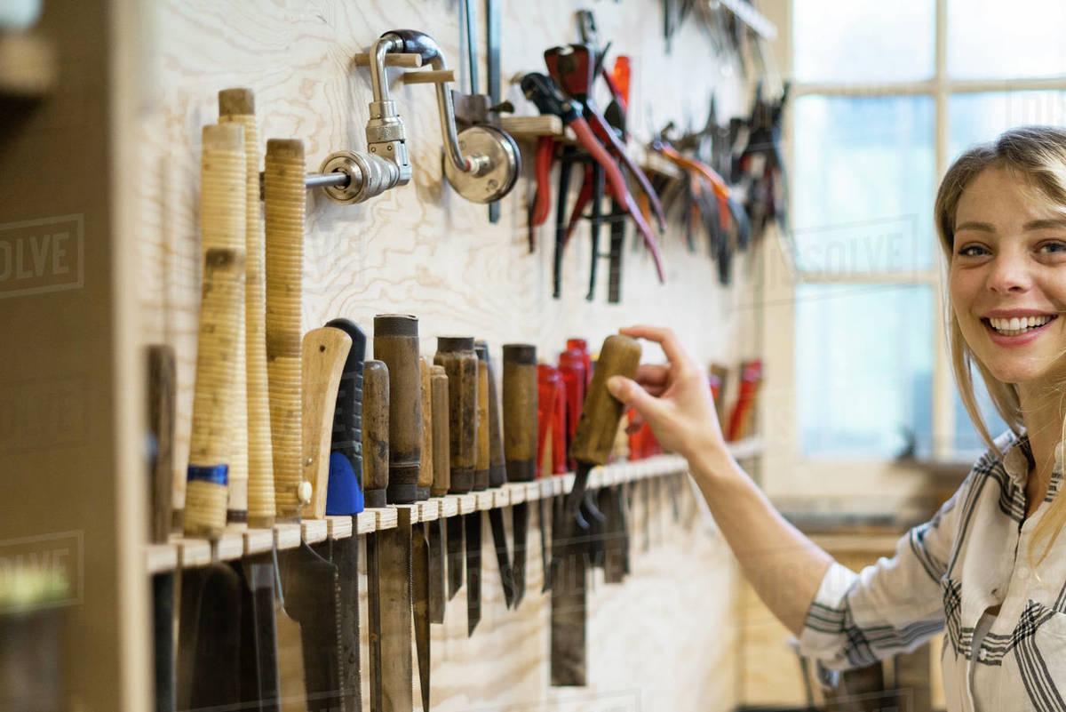 Woman holding hand tool in workshop - Royalty-free Stock Photo | Dissolve