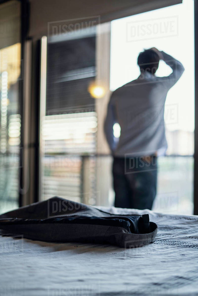 Thoughtful young man standing by the window - Stock Photo - Dissolve