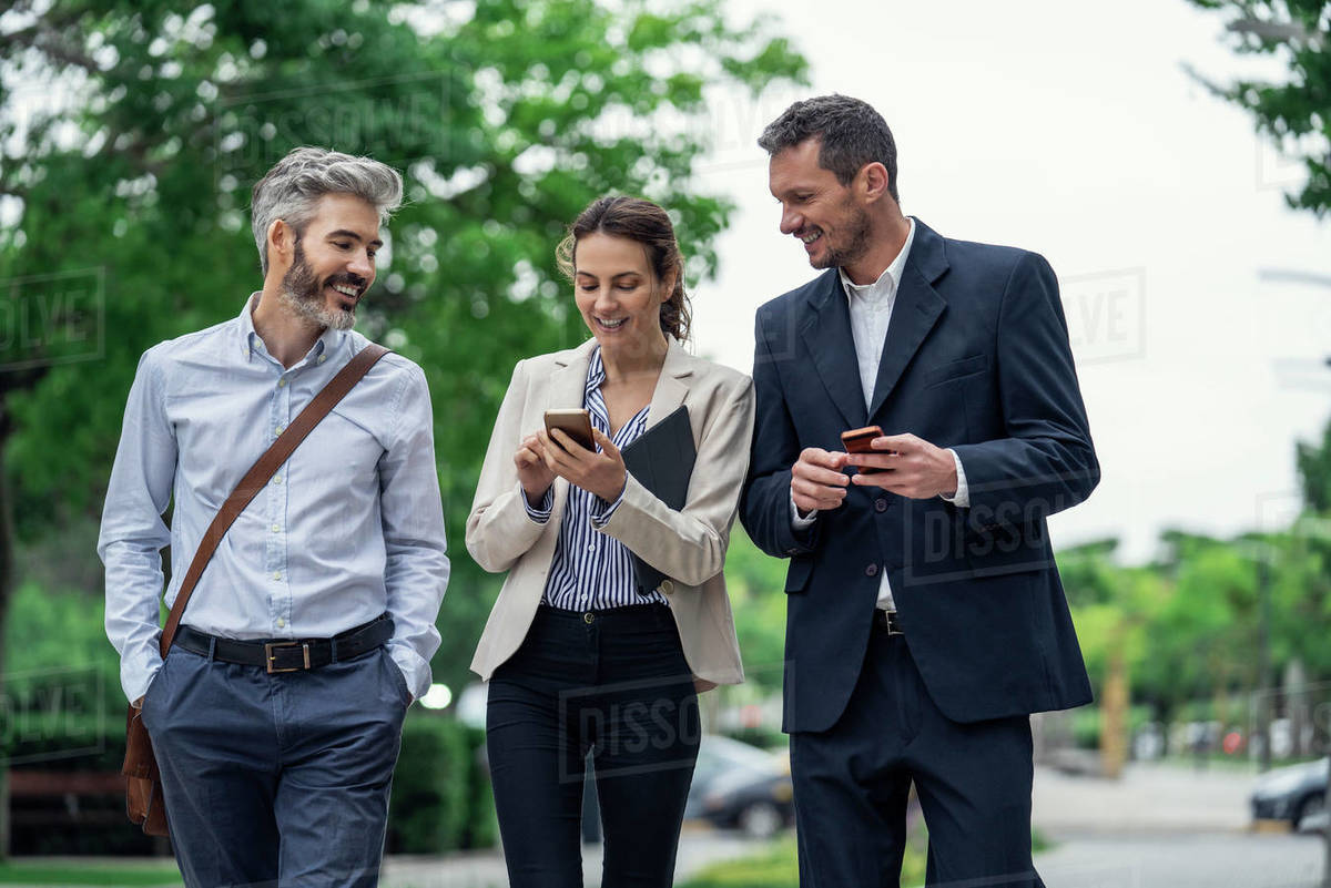 Business people using smartphones in public park - Royalty-free Stock ...