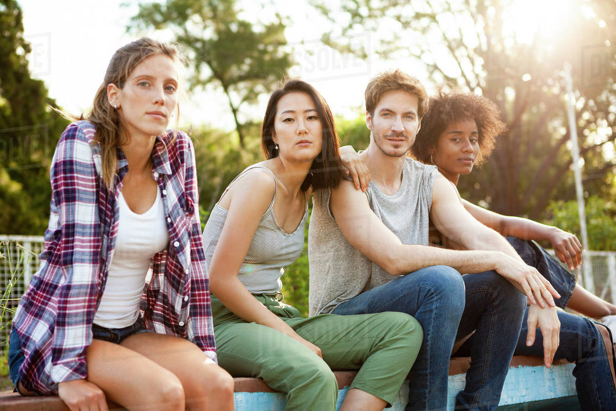 Group of young friends sitting together in park - Stock Photo - Dissolve