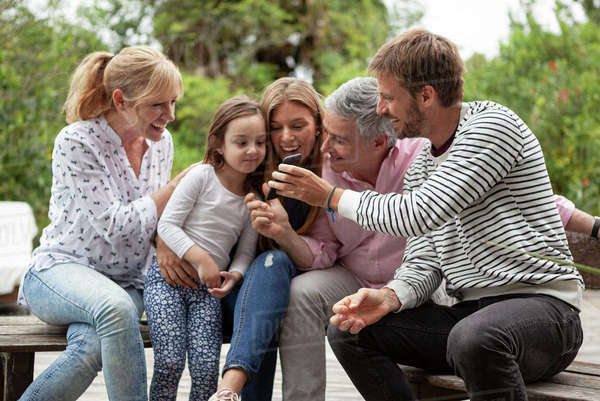 Family looking at smartphone - Stock Photo - Dissolve