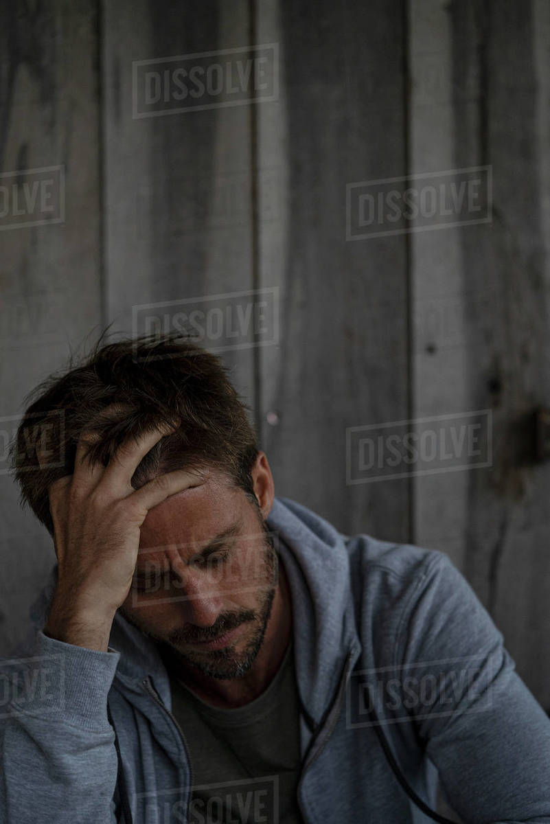 Sad man sitting in stilt hut - Royalty-free Stock Photo | Dissolve