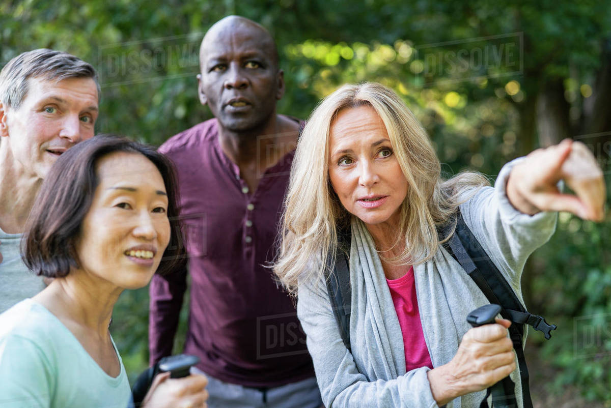Senior woman giving directions to diverse group of people while ...
