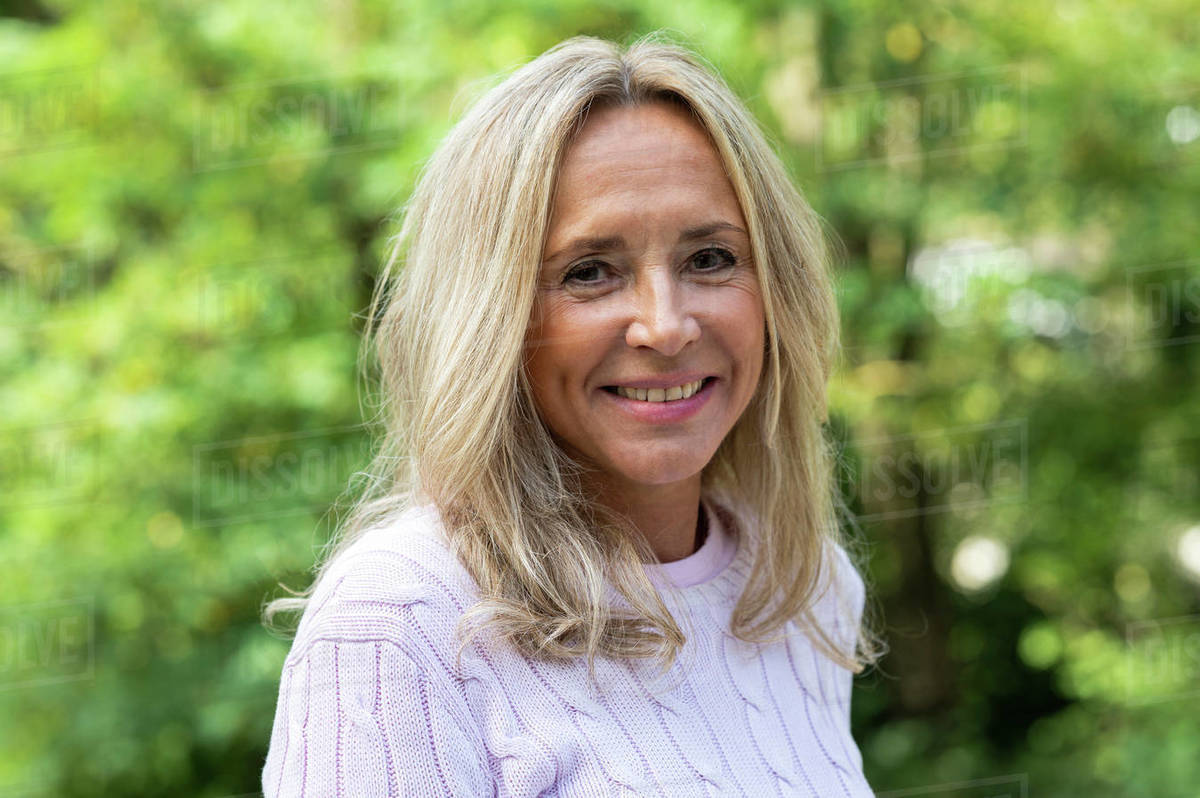 Mid-shot portrait of middle age woman looking at camera while posing ...
