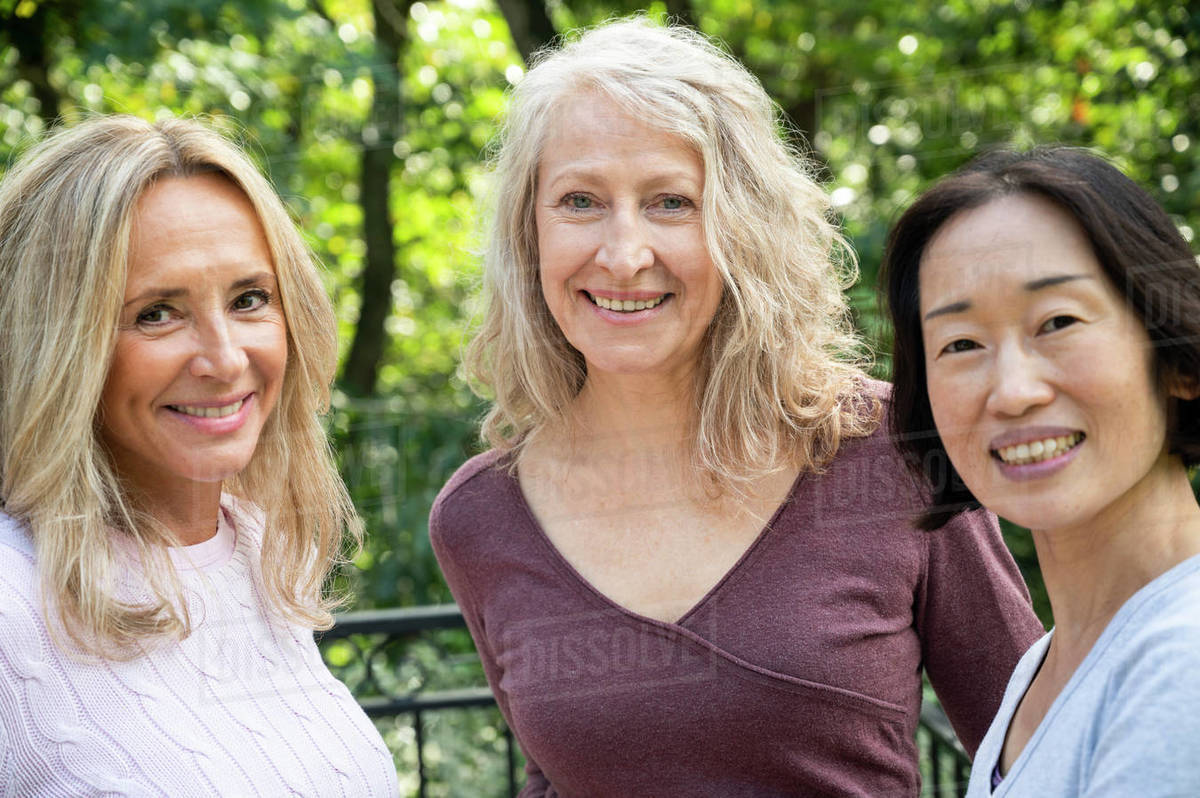 Portrait of three middle aged lady friends looking at camera while ...