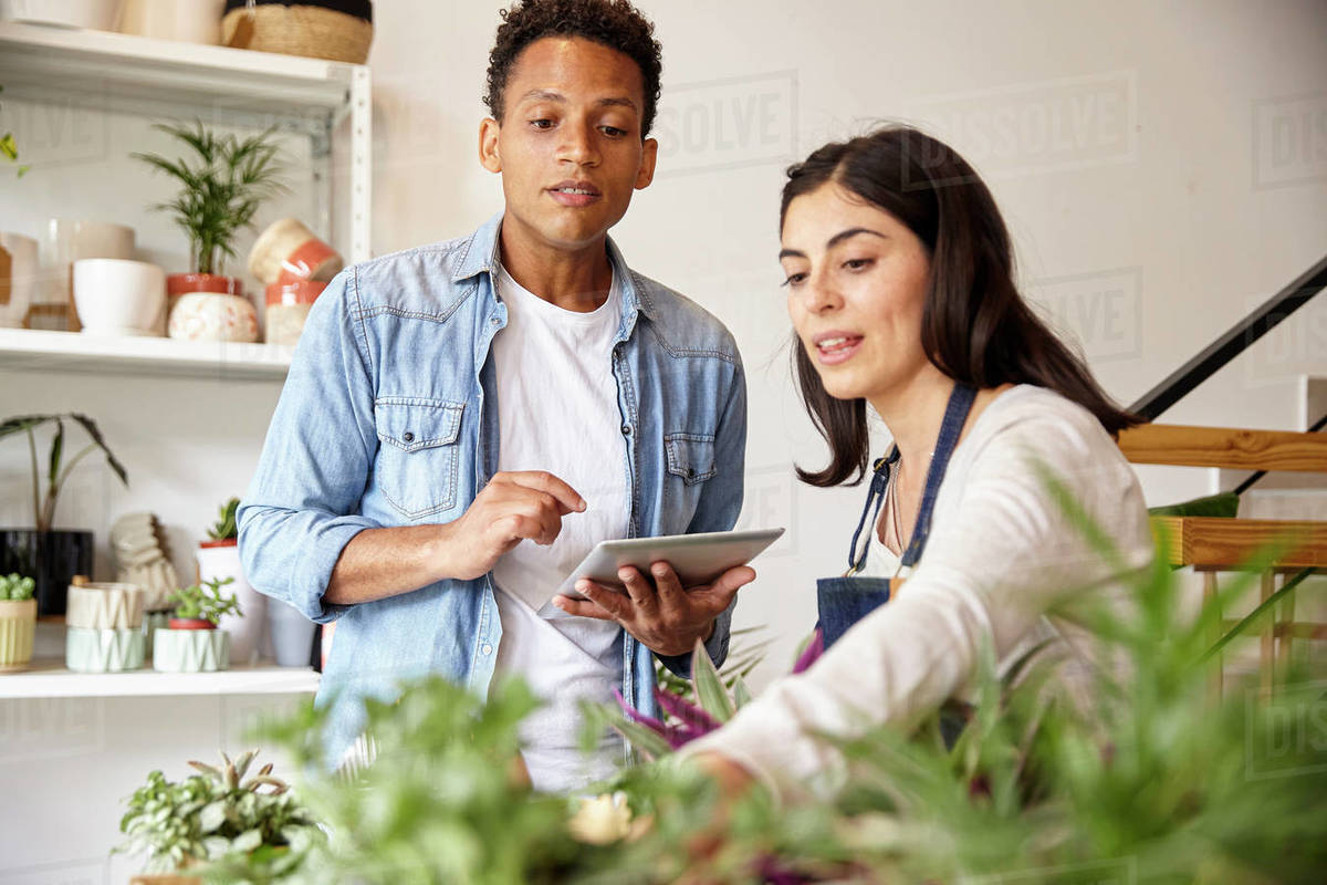Small business plant shop owners taking inventory on digital tablet ...