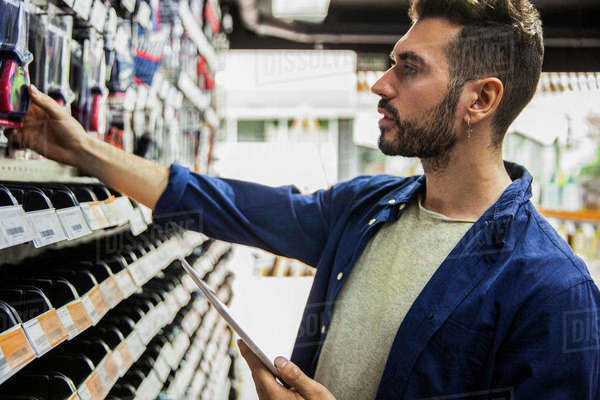 Male hardware shop worker taking inventory on digital tablet - Royalty ...