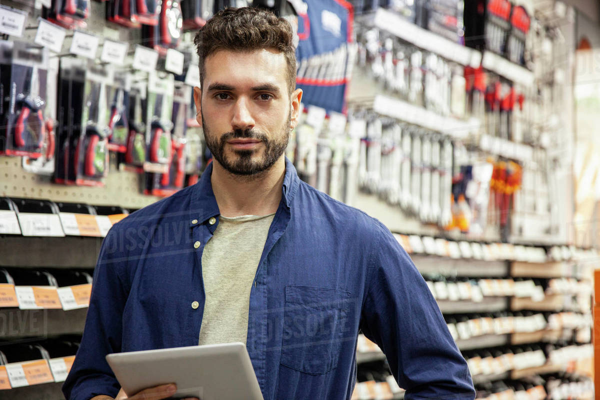 Hardware shop owner looking at the camera while holding digital tablet ...
