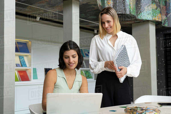 Mid-shot of female Latin-American interior designer and her assistant ...