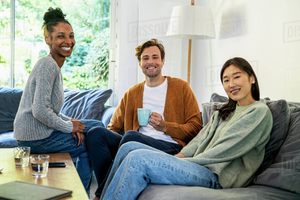 Small group of friends gathered in living room looking at the camera ...
