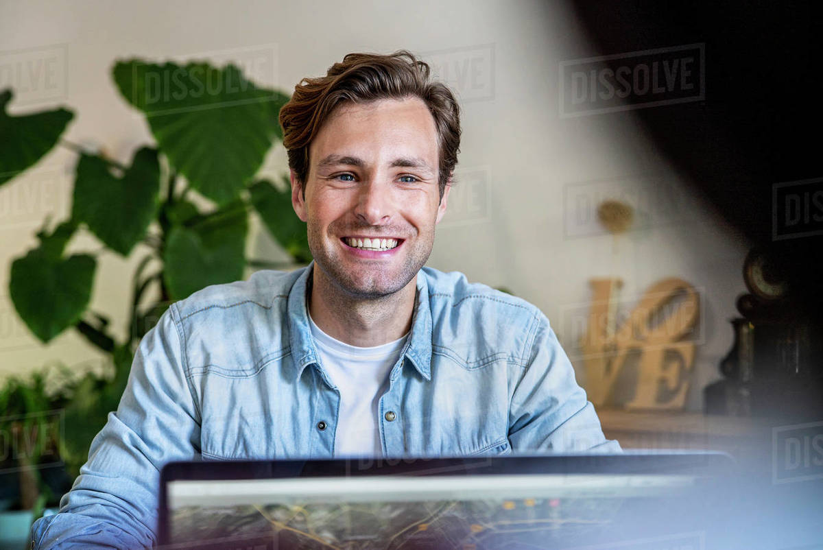 Cheerful male graphic designer sitting at desk using laptop - Stock ...