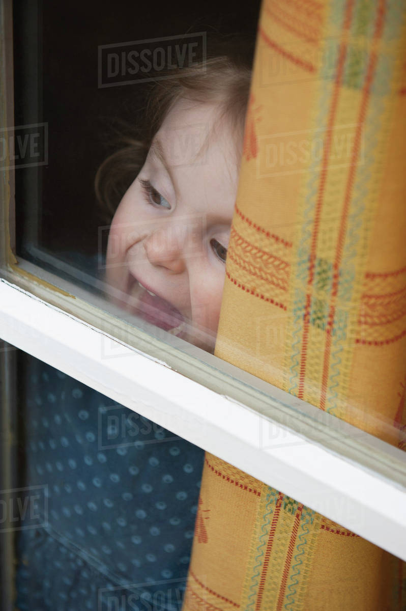 Little girl looking through window - Stock Photo - Dissolve