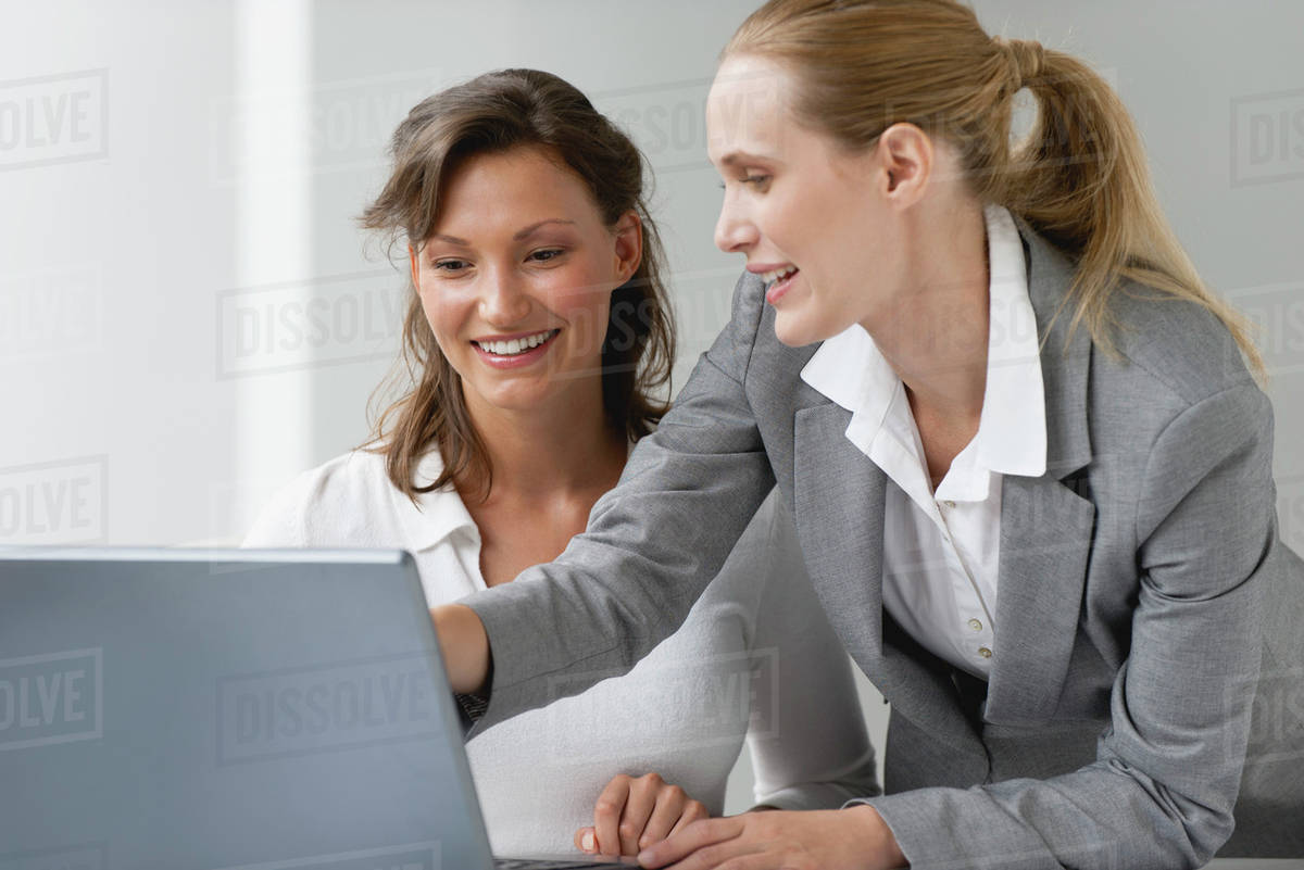 Female colleagues working together on laptop computer - Royalty-free ...