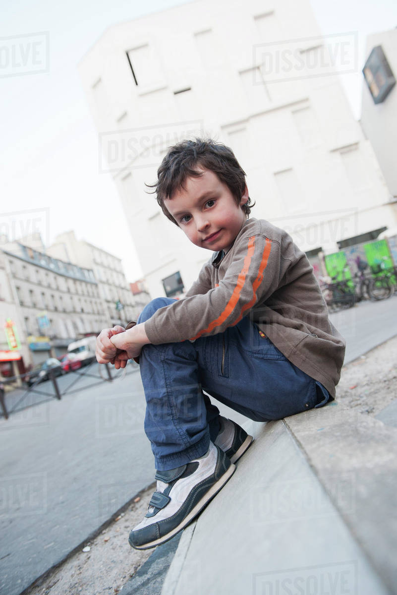 Boy sitting on curb, portrait - Royalty-free Stock Photo | Dissolve