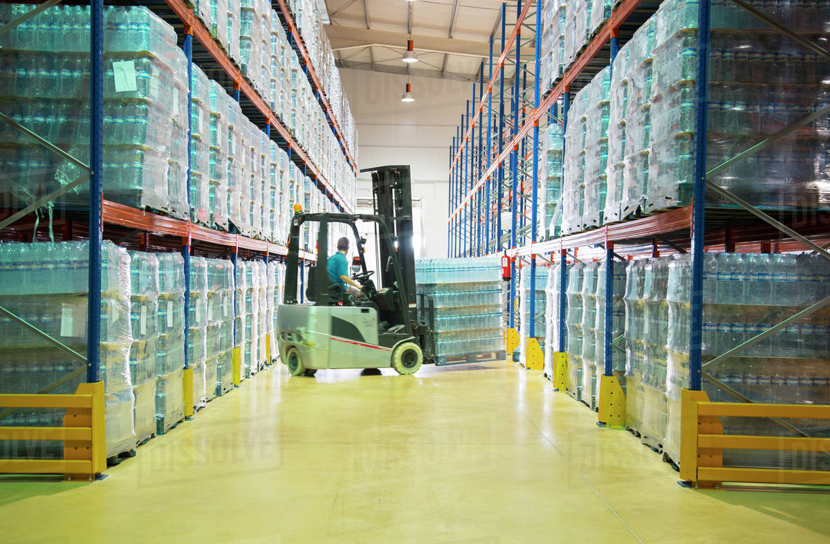 Worker moving pallets with forklift in warehouse - Stock Photo - Dissolve