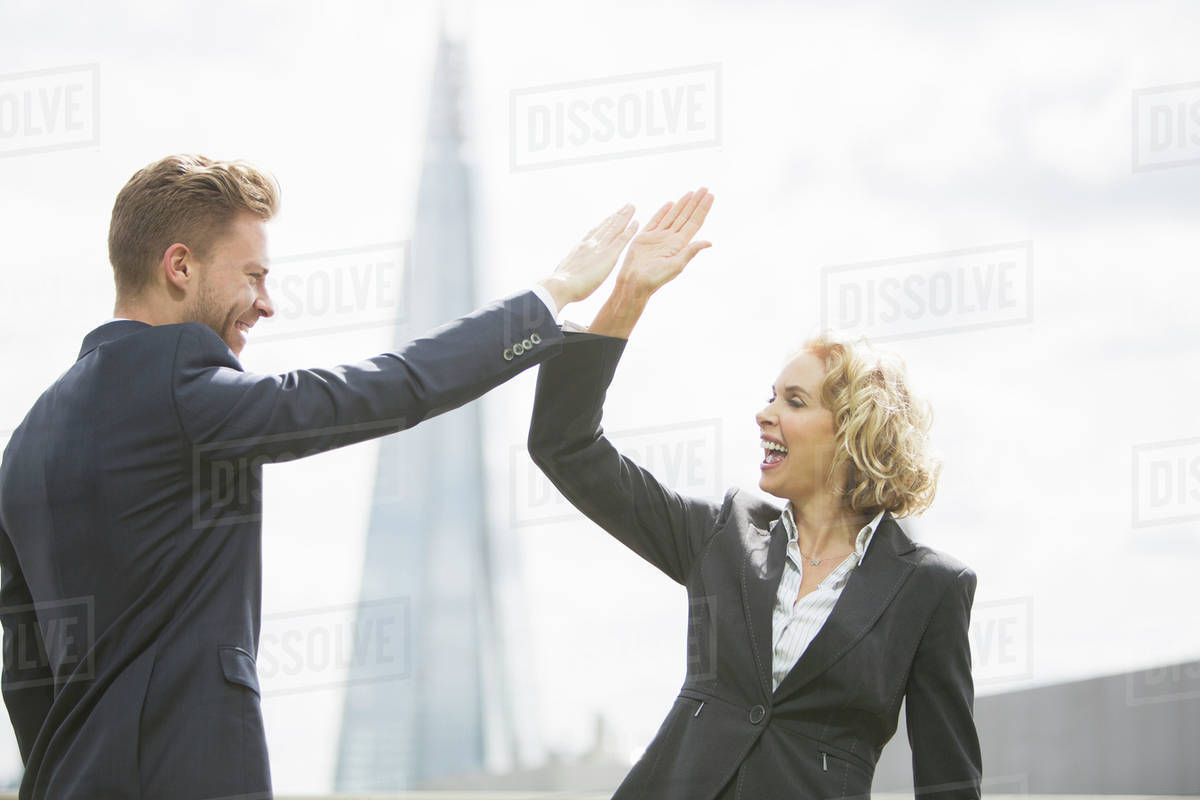 Business people high fiving outdoors - Royalty-free Stock Photo | Dissolve