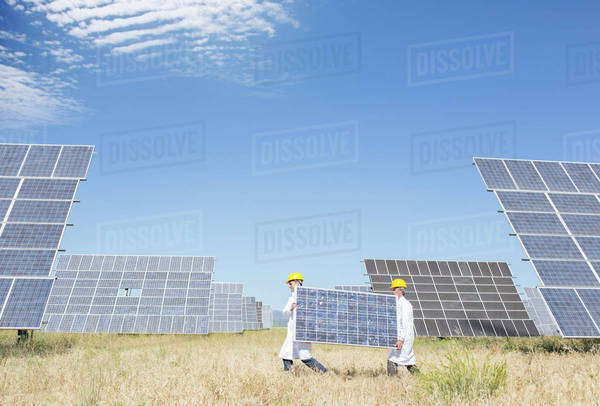 Scientists carrying solar panel in rural landscape - Stock Photo - Dissolve