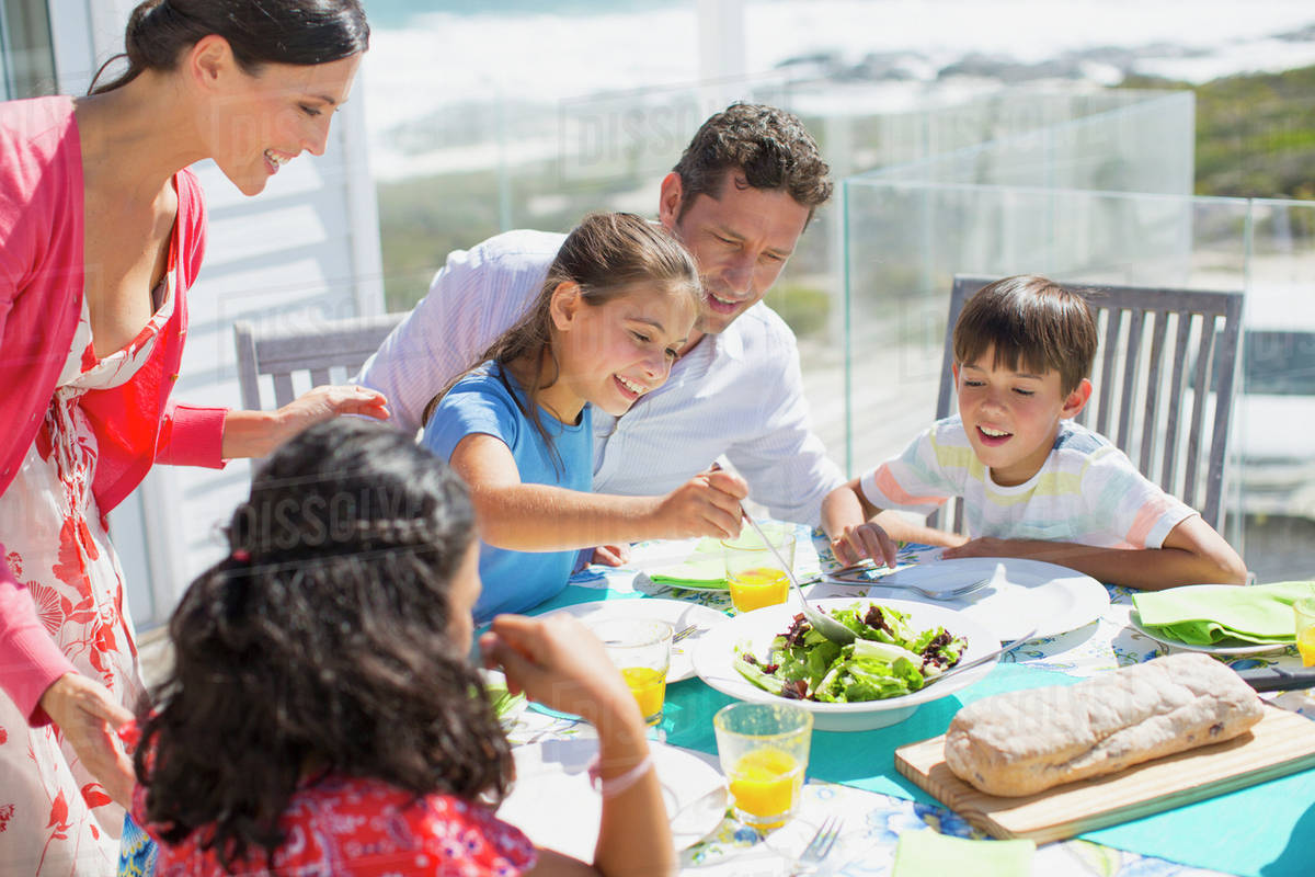 Family eating lunch at table on sunny patio - Royalty-free Stock Photo ...