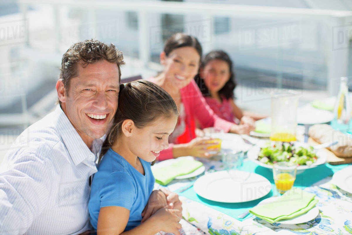 Family eating lunch at table on sunny patio - Royalty-free Stock Photo ...