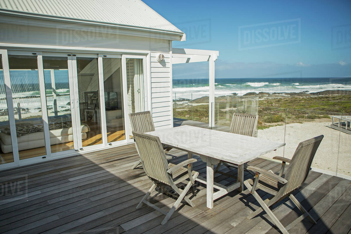 Table and chairs on balcony overlooking beach - Royalty-free Stock ...