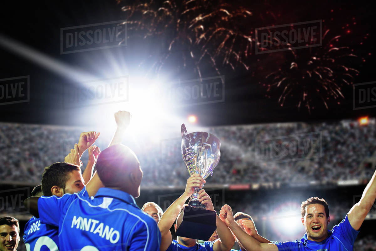 Soccer team celebrating with trophy on field - Royalty-free Stock Photo ...