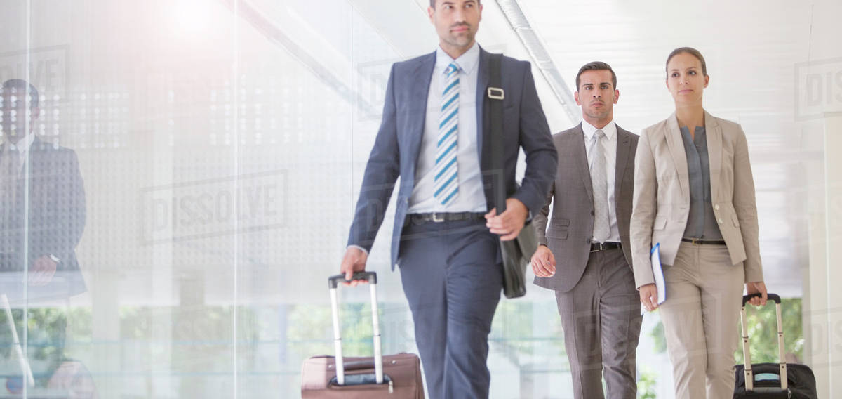 Business people pulling suitcases in corridor - Stock Photo - Dissolve