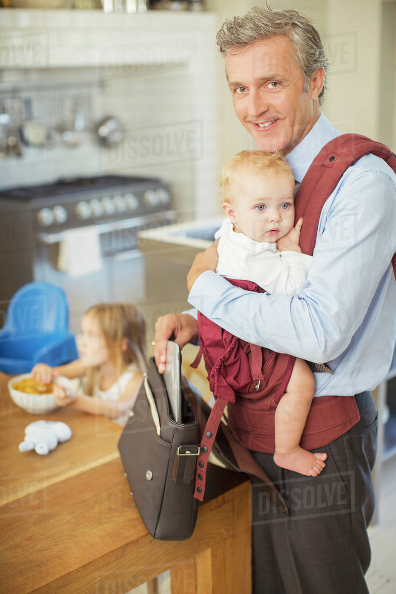 Businessman carrying baby in kitchen - Royalty-free Stock Photo | Dissolve
