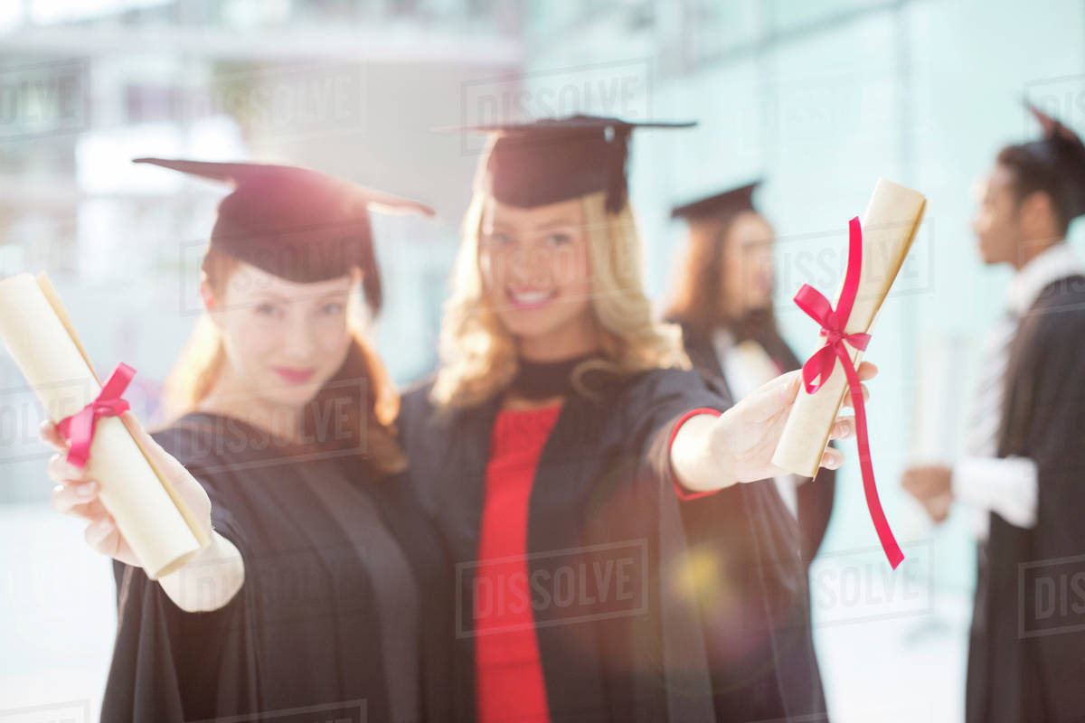 Smiling graduates holding diplomas - Stock Photo - Dissolve