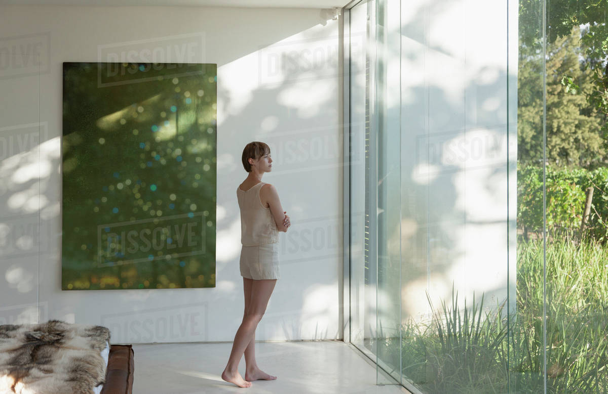 Woman standing at window in modern bedroom - Stock Photo - Dissolve