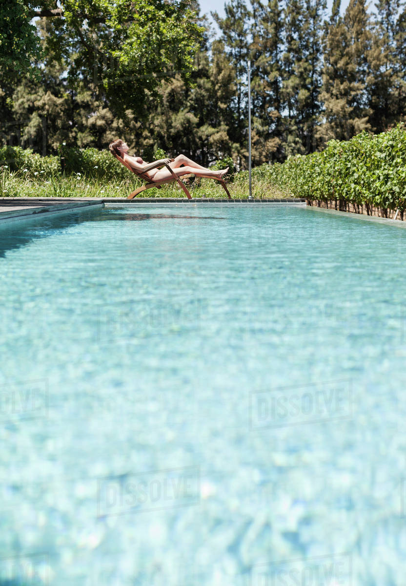 Woman relaxing by swimming pool - Stock Photo - Dissolve