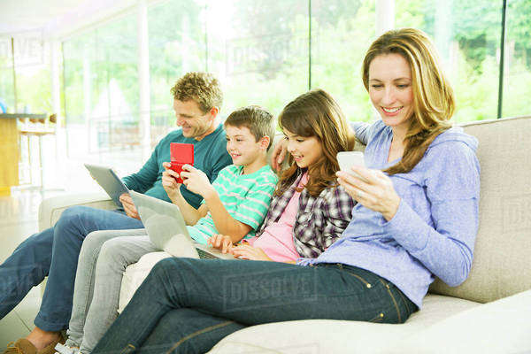 Family using technology on sofa - Stock Photo - Dissolve