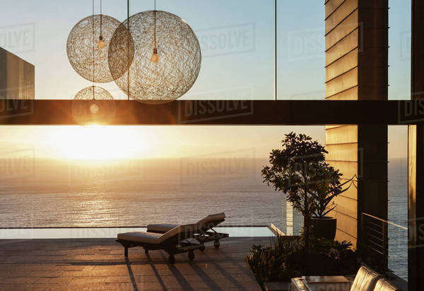 Patio of modern house overlooking ocean at sunset - Stock Photo - Dissolve