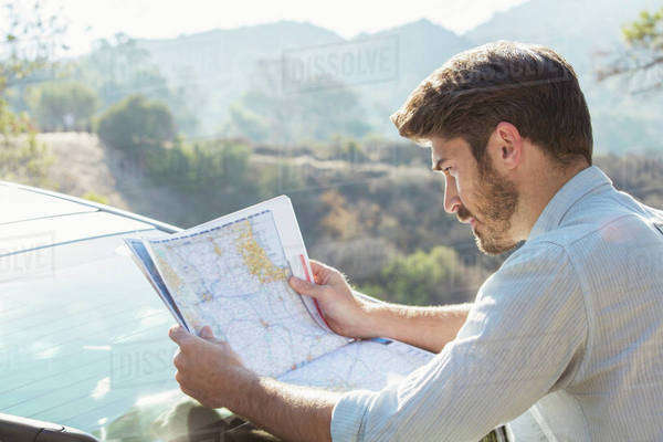 Man looking at map outside car - Royalty-free Stock Photo | Dissolve