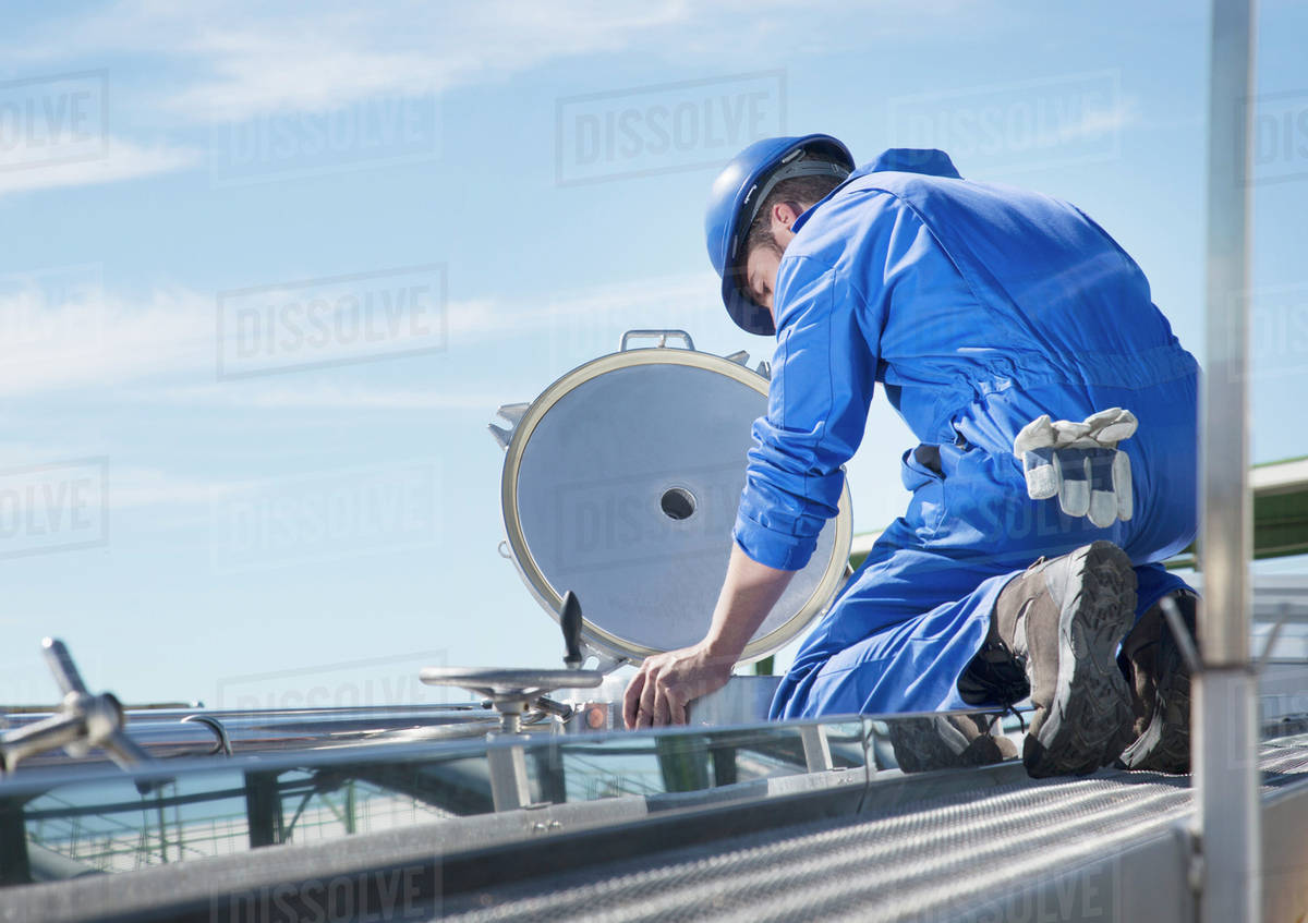 Worker on platform looking down at milk tanker - Stock Photo - Dissolve