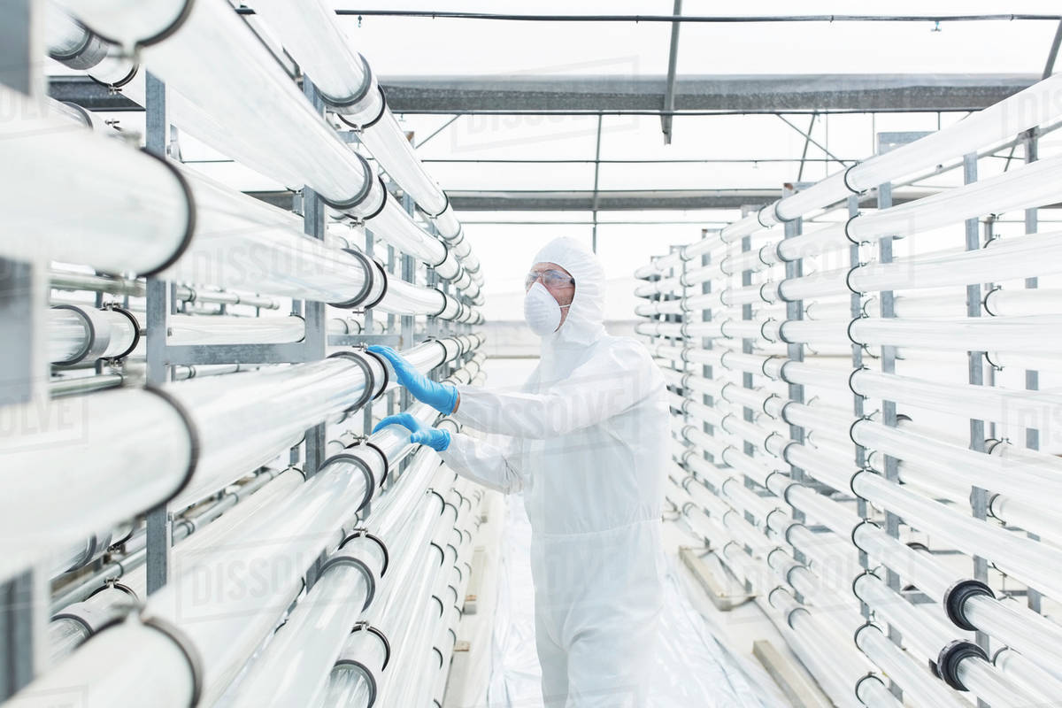 Engineer in clean suit examining pipes in laboratory - Royalty-free ...