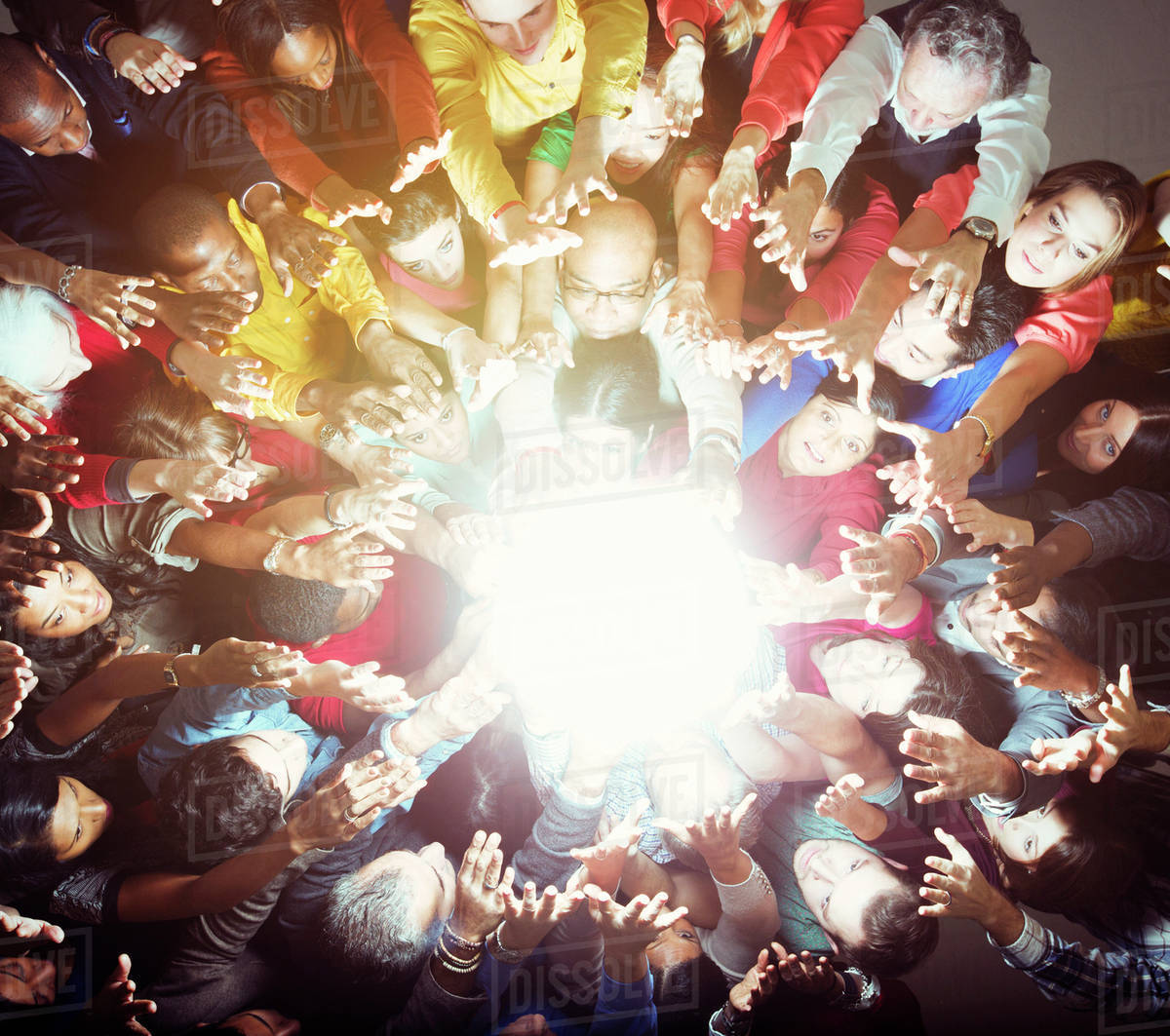 Diverse crowd reaching for bright light - Stock Photo - Dissolve