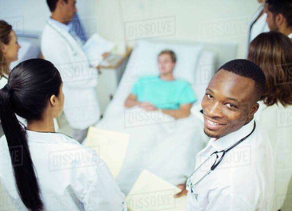 Doctor standing with residents in hospital room - Stock Photo - Dissolve