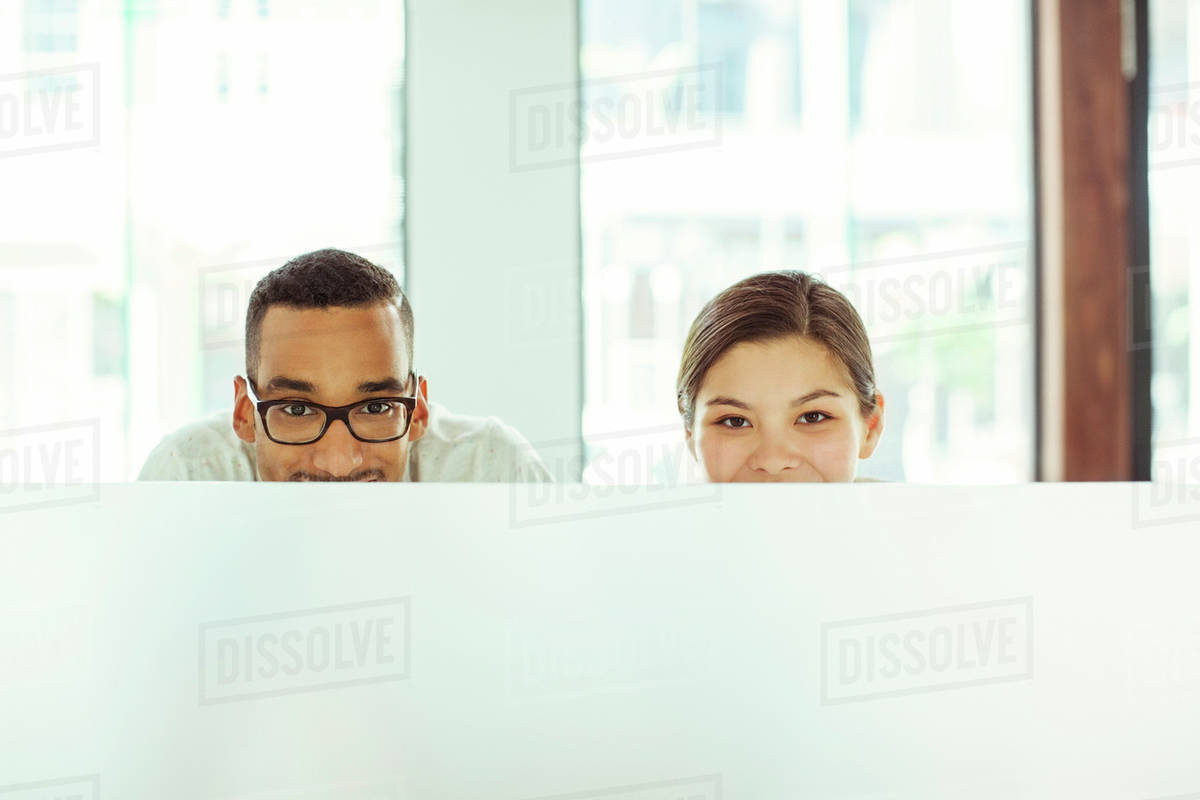 People peering over cubicle in office - Stock Photo - Dissolve