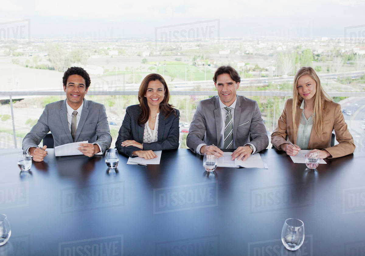 Portrait of smiling business people sitting at table in conference room ...