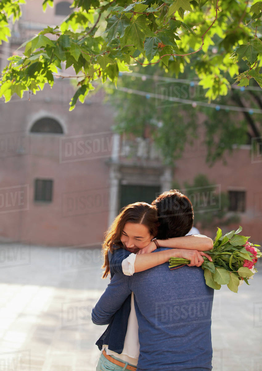Woman holding flowers and hugging man - Stock Photo - Dissolve