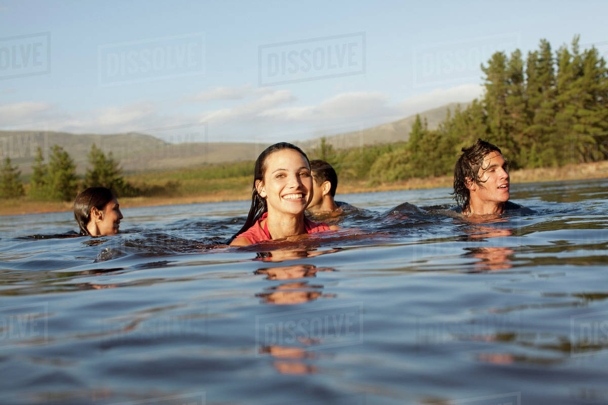 Smiling friends swimming in lake - Royalty-free Stock Photo | Dissolve