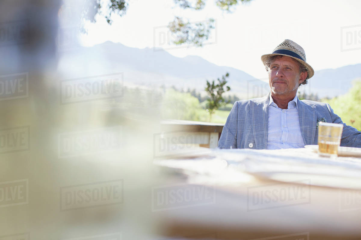 Older man sitting at outdoor dinning table - Stock Photo - Dissolve