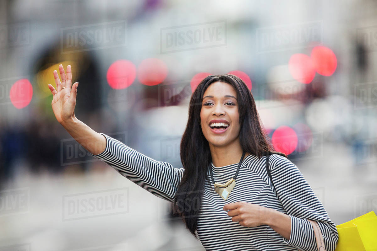 Woman waving for taxi on city street - Royalty-free Stock Photo | Dissolve