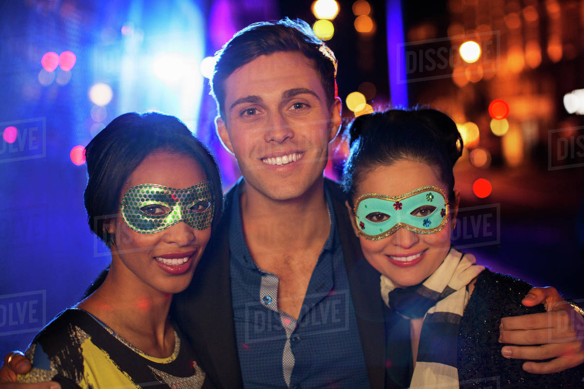 Friends smiling together on city street at night - Stock Photo - Dissolve
